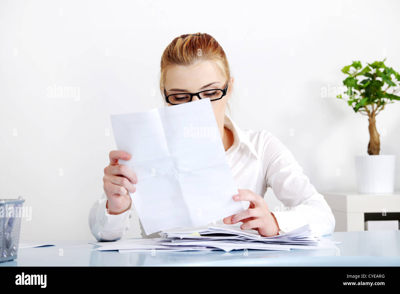 Sitting caucasian woman in glasses reading files behind the desk Stock ...