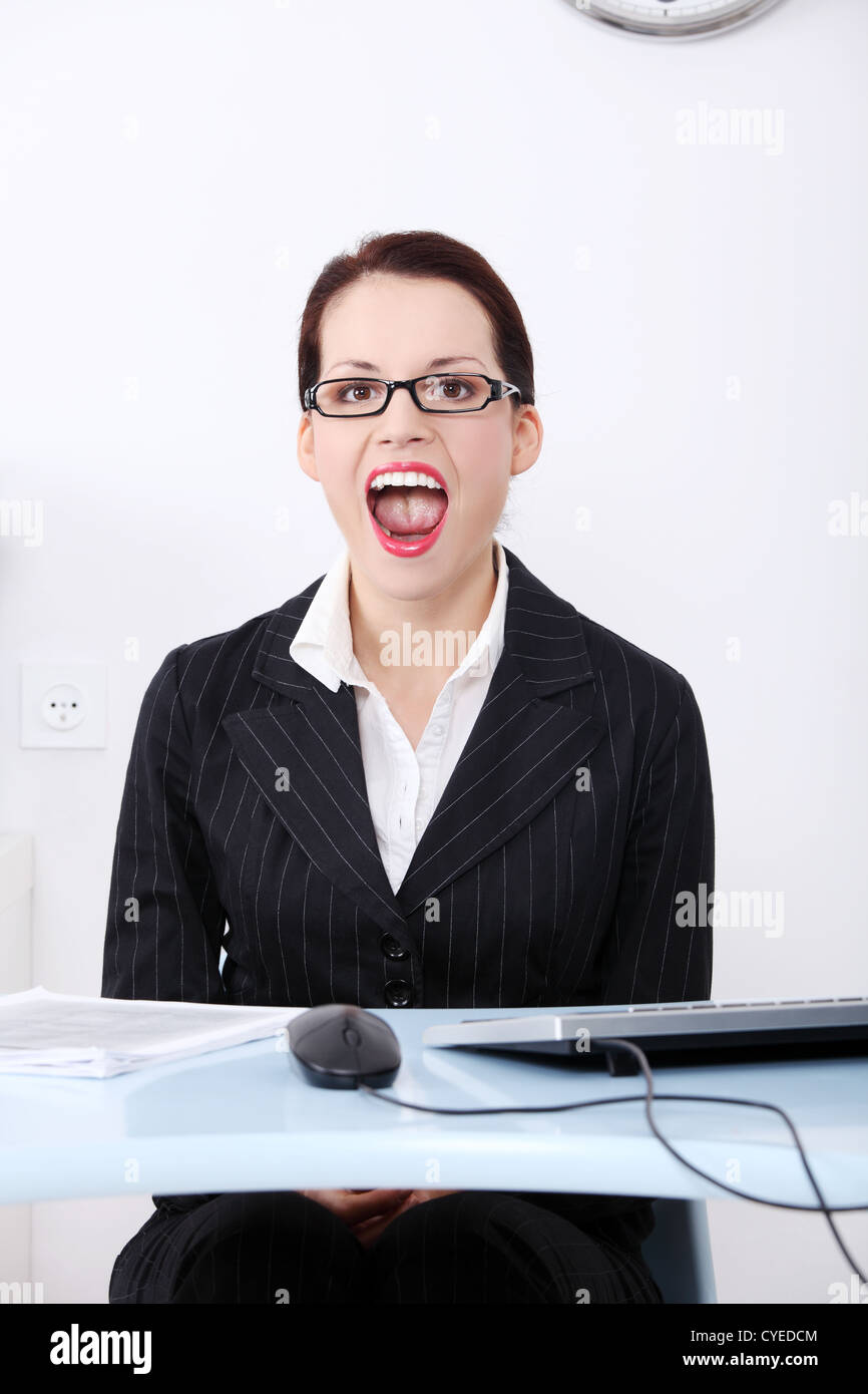 Pretty caucasian screaming businesswoman sitting behind the desk in the ...