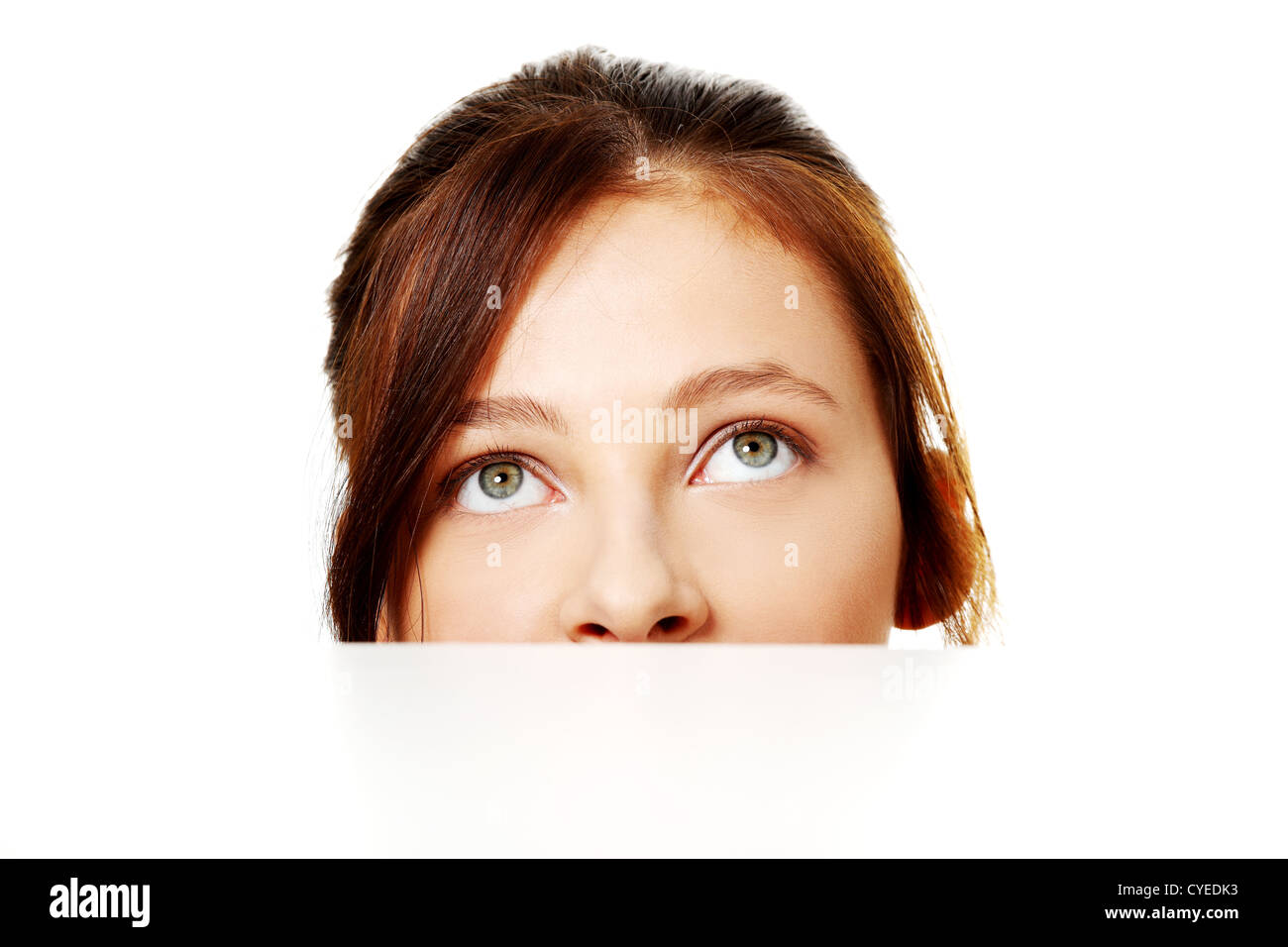 Pretty teen brunette student hiding behind sheet of paper Stock Photo ...