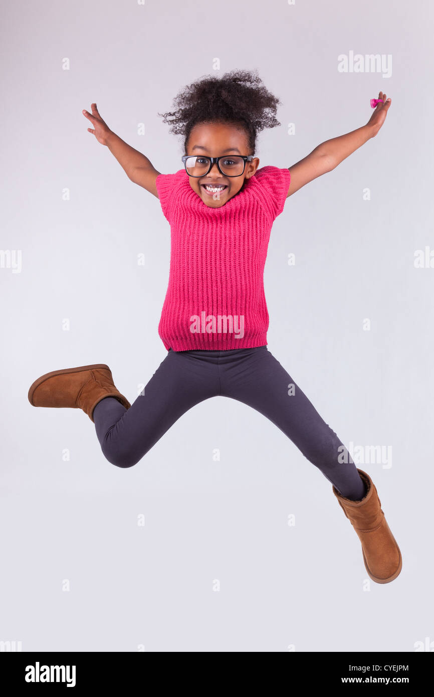 Portrait of cute Young African American girl jumping, over gray ...