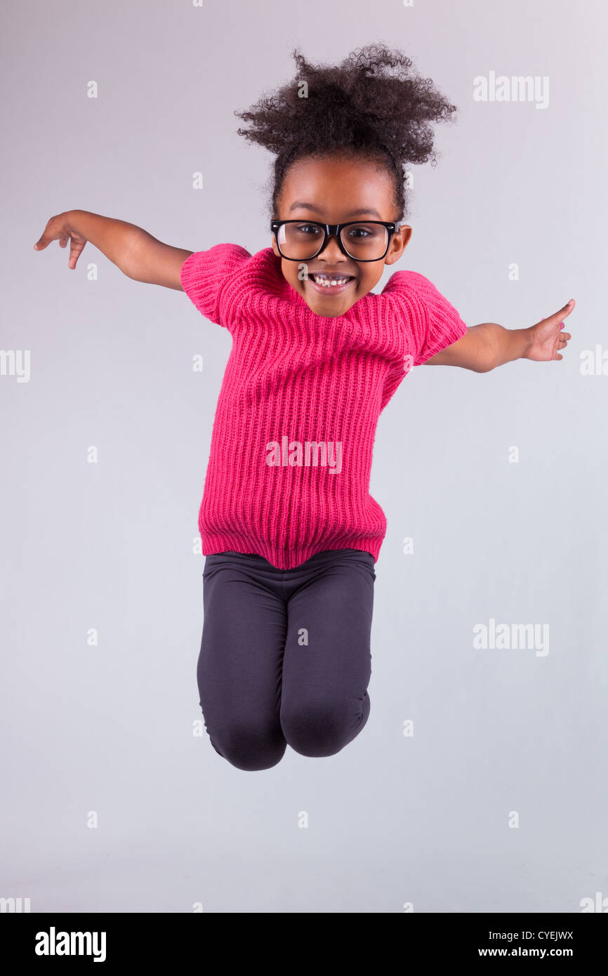 Portrait of cute Young African American girl jumping, over gray ...