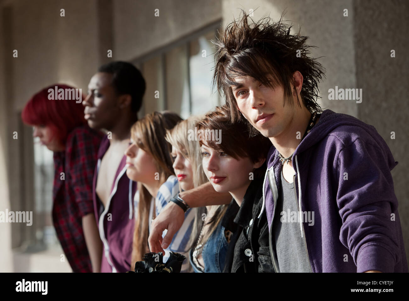 Young punk boy looks at the camera as his friends look away into the ...