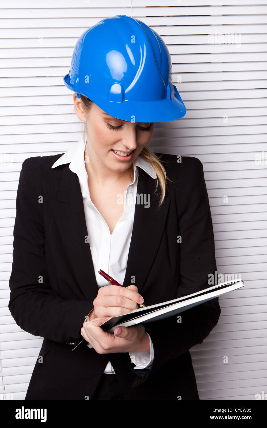 Female Inspector Checking Notes in a blue hard hat conceptual of ...