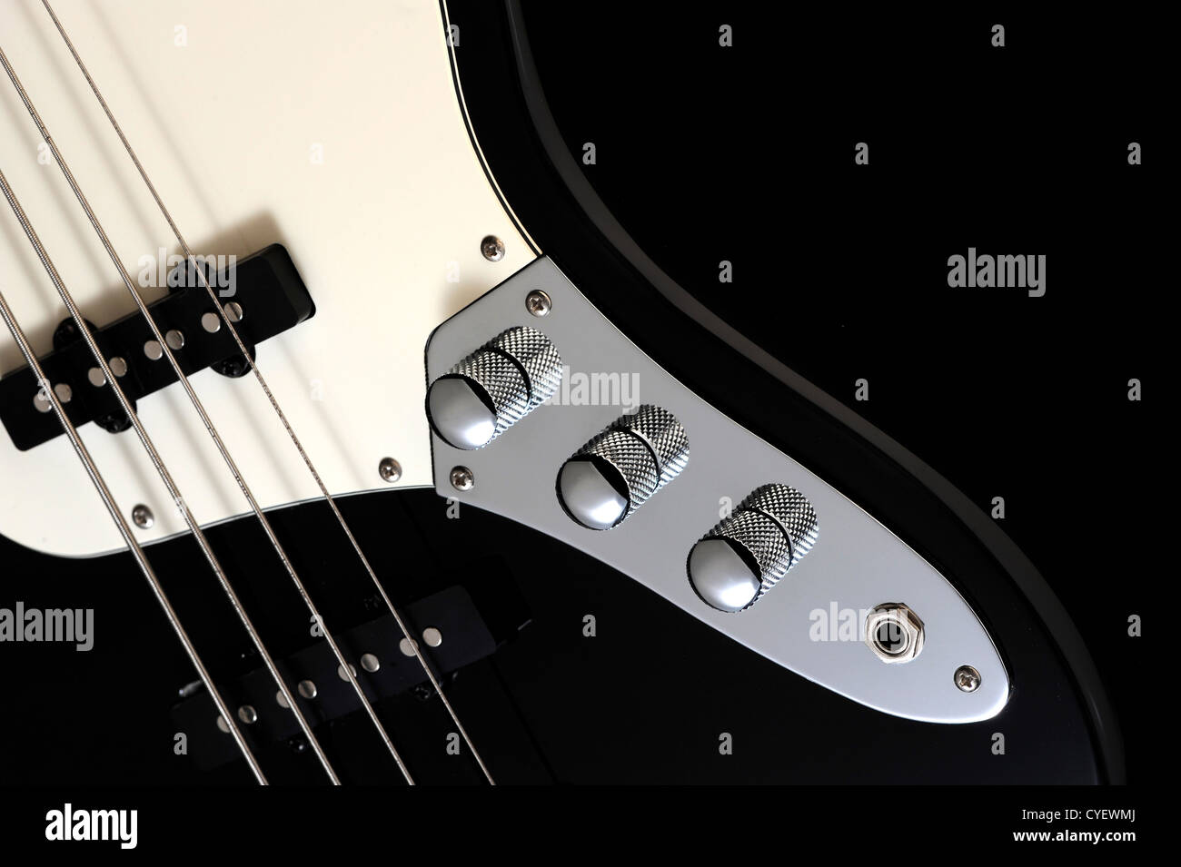 a close up of volume knob of a black electric bass glossy on dark ...