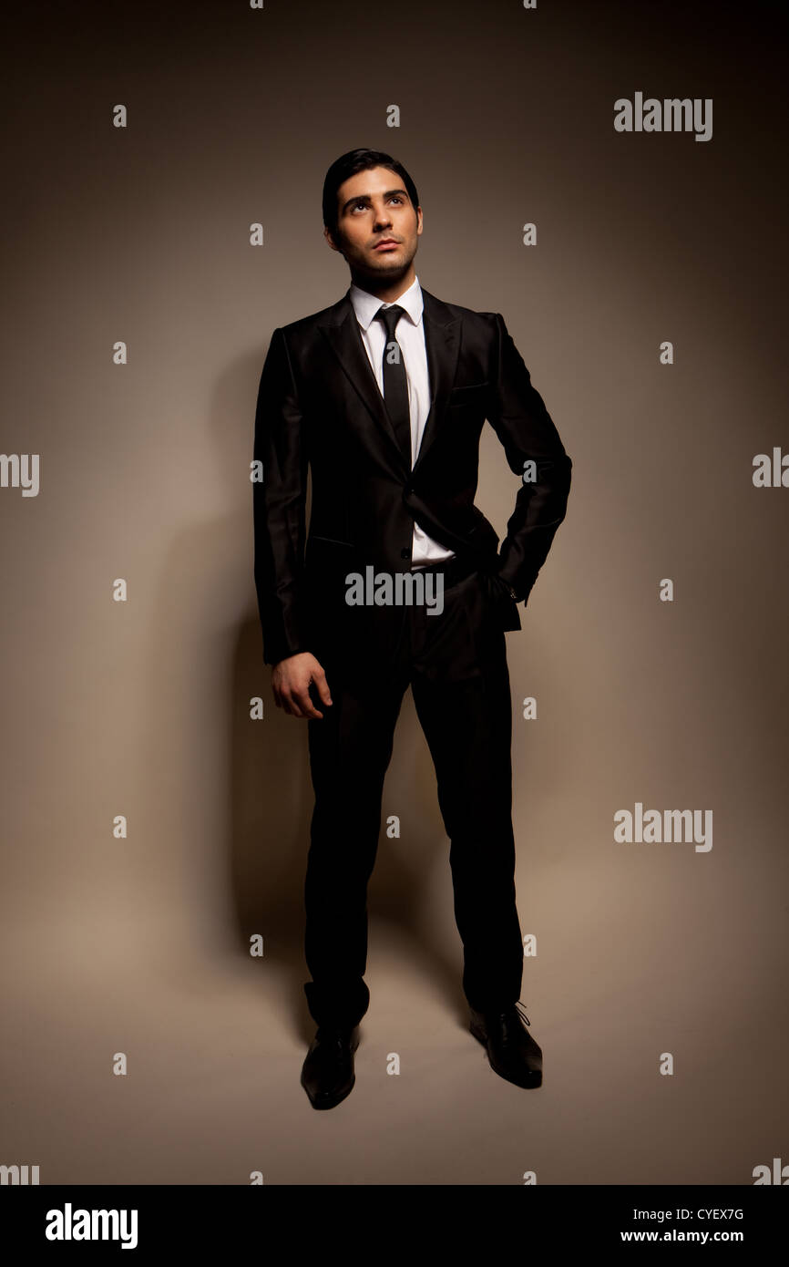 Pensive Executive Businessman standing against brown studio background ...