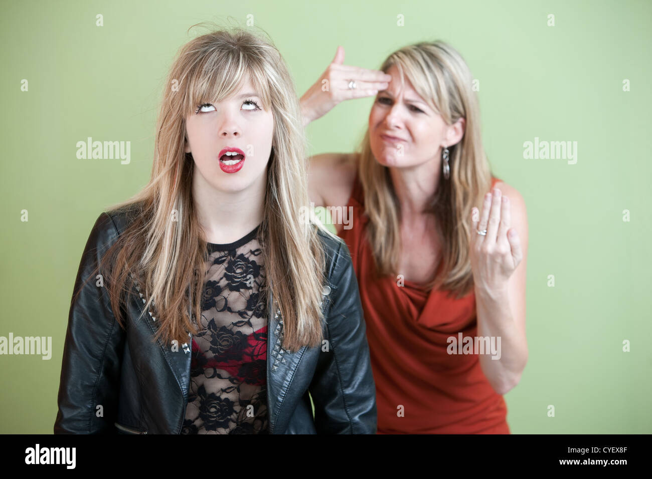 Frustrated mother behind angry daughter in provocative clothing Stock ...