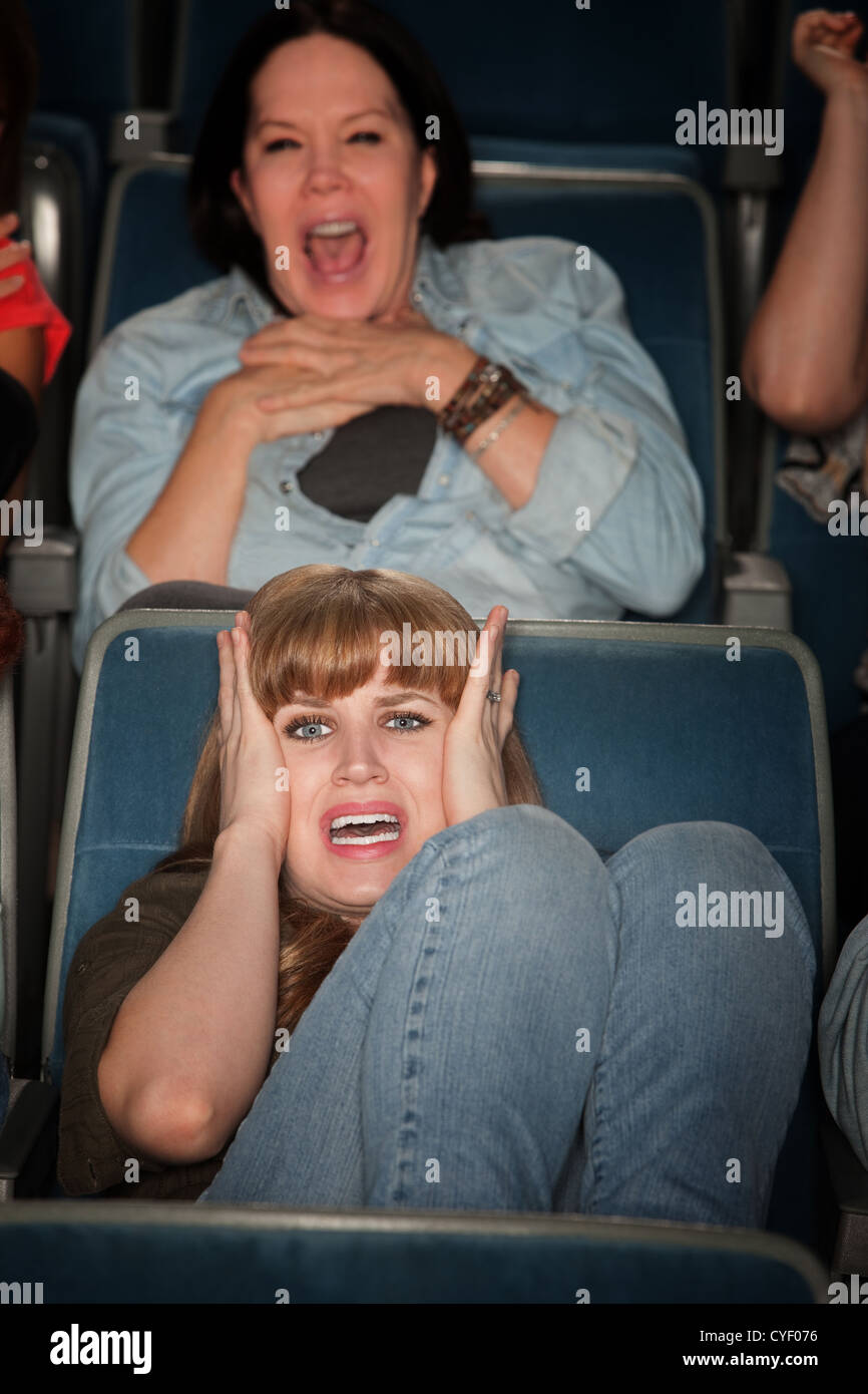 Screaming women watch scary movie in theater Stock Photo - Alamy
