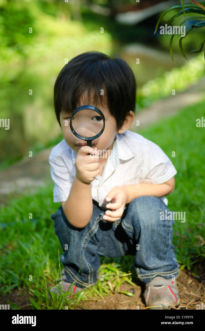 Little boy exploring nature by magnifier Stock Photo - Alamy