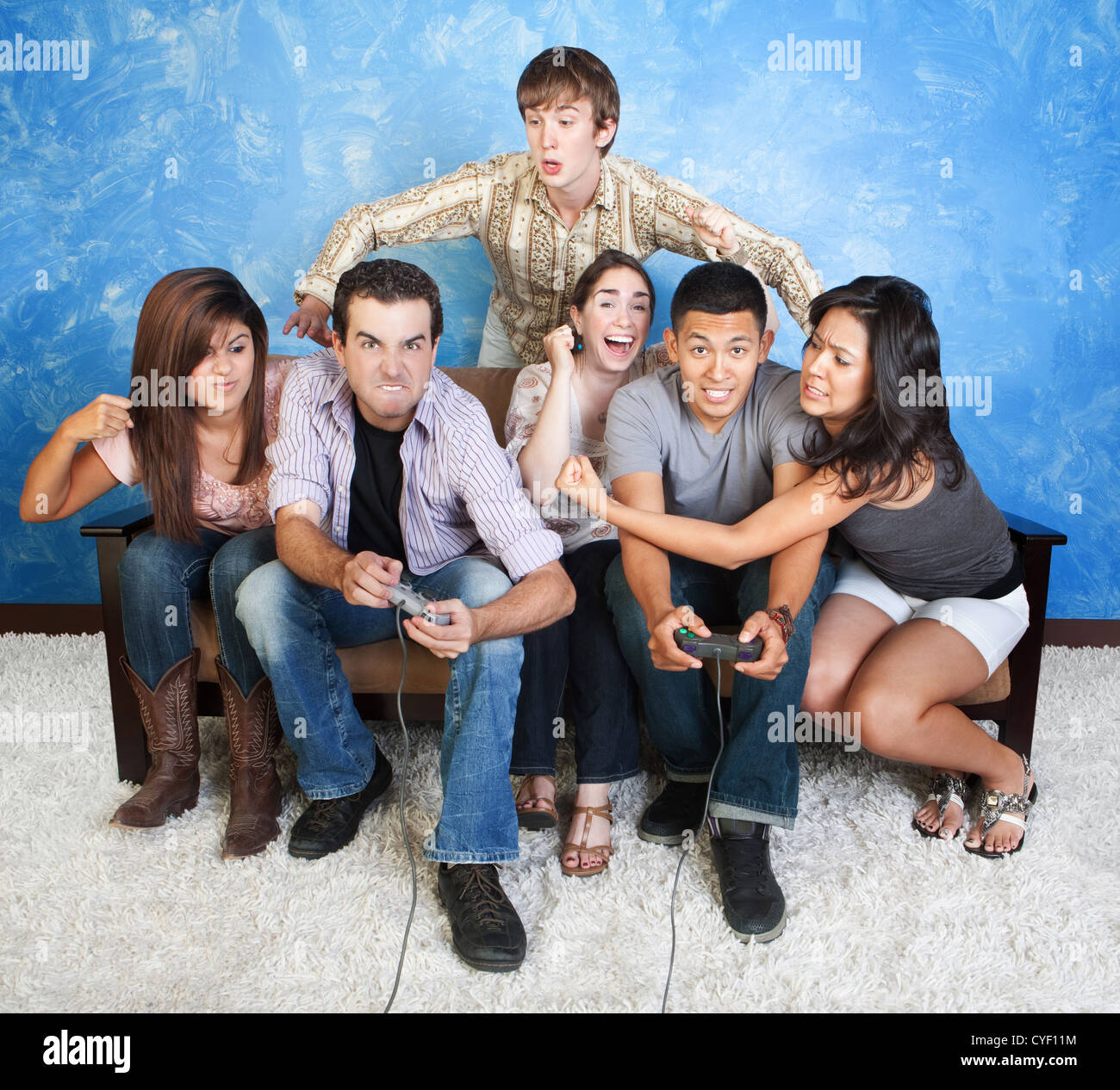 Diverse group of young people fight over video games Stock Photo - Alamy