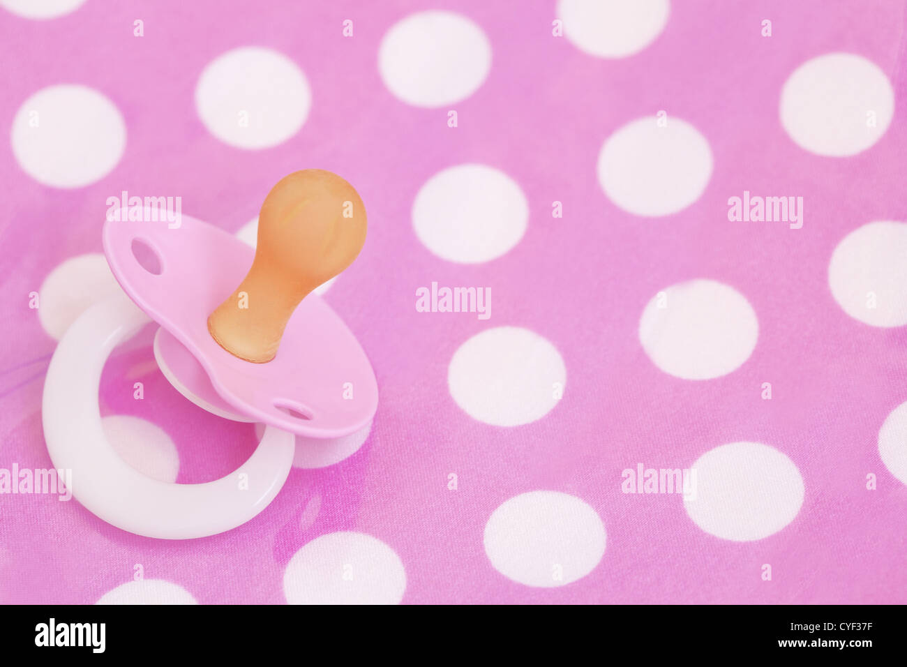 Pink baby dummy on polka dot background Stock Photo - Alamy