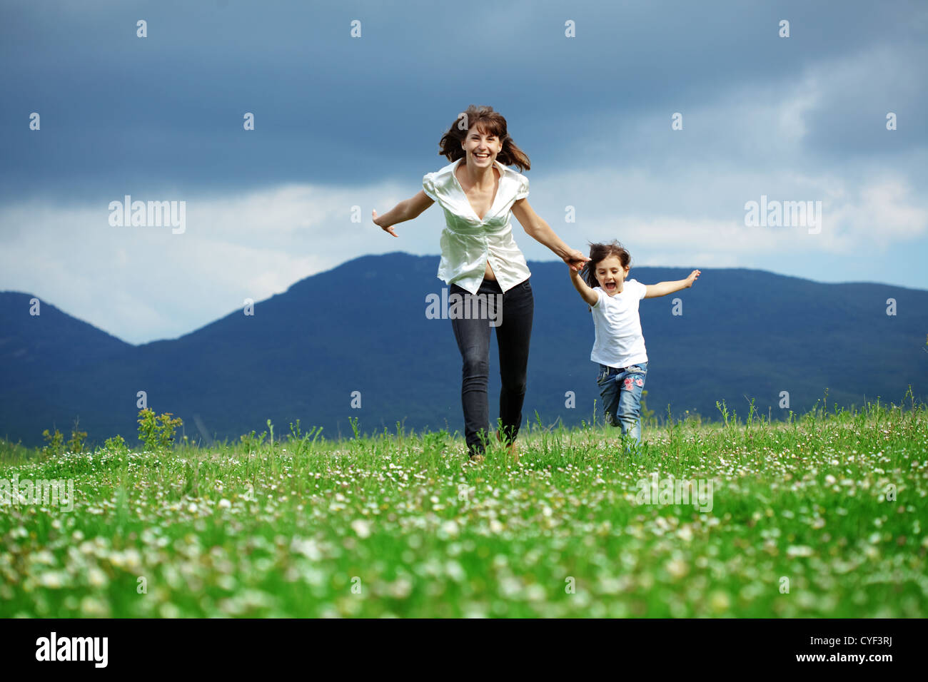 Happy young mother with daughter running in field Stock Photo - Alamy