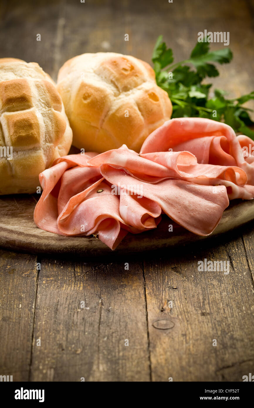 Sliced soft mortadella sausage on wooden table with bread Stock Photo ...