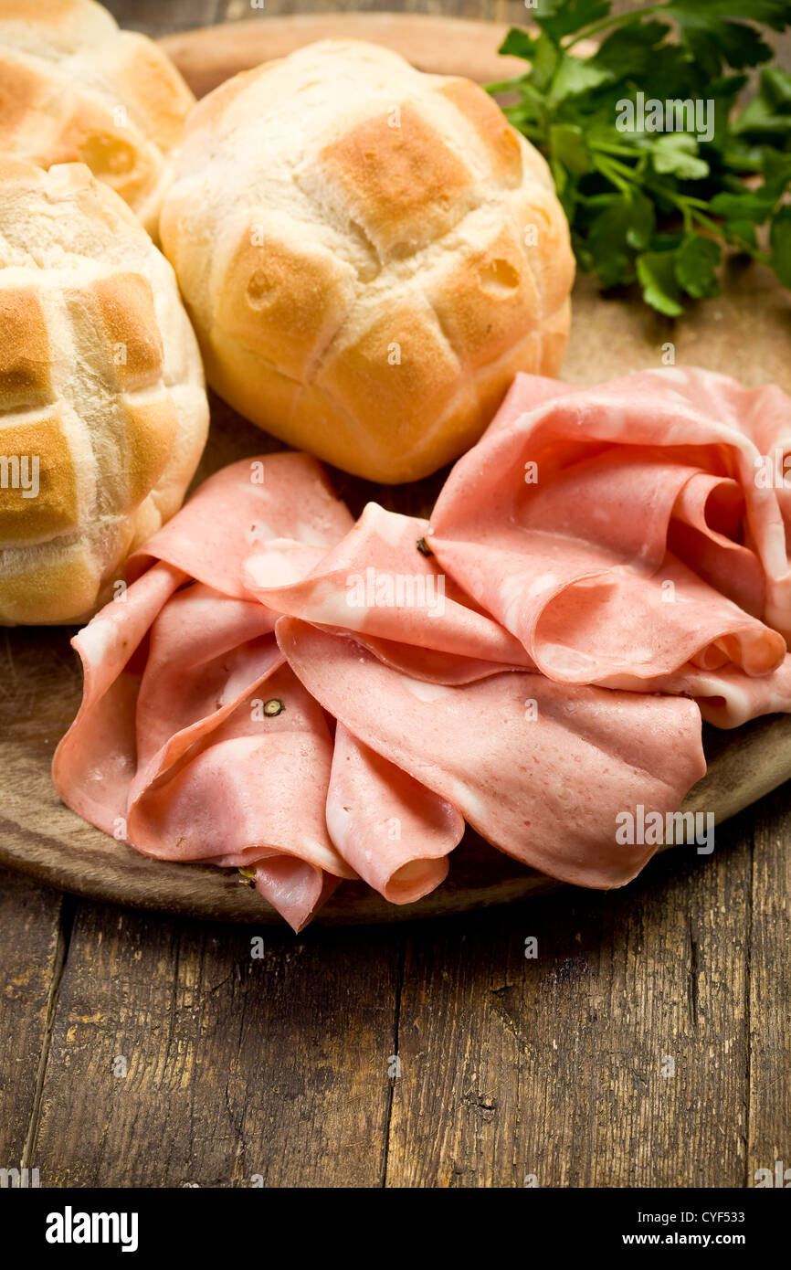 Sliced soft mortadella sausage on wooden table with bread Stock Photo ...