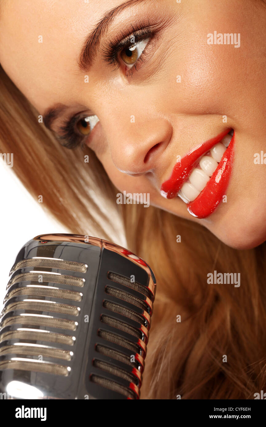 Gorgeous smiling blonde woman with vivid red lips using a microphone ...