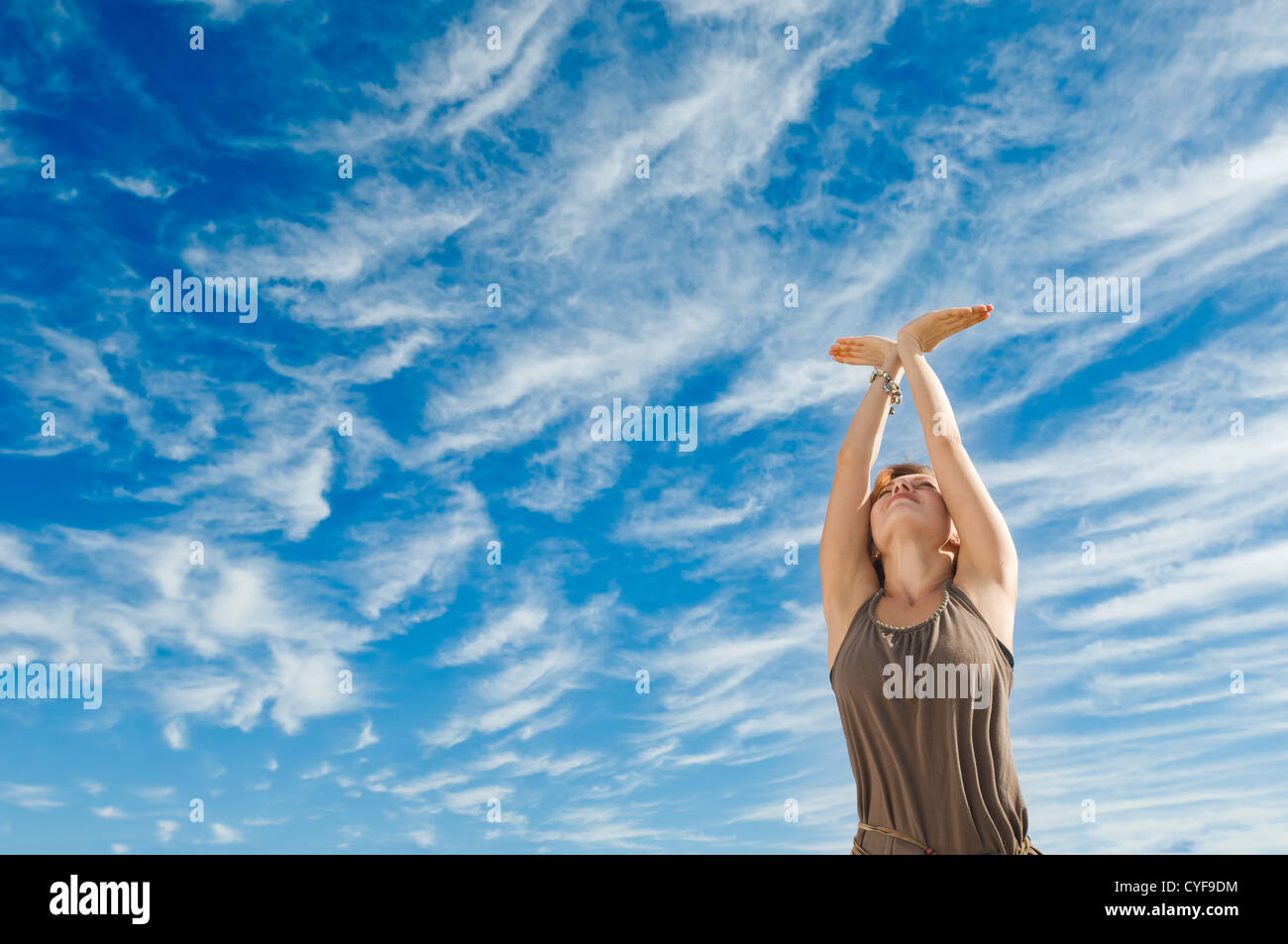 Beautiful young dancer performing yoga-dance outdoors with blue sky and ...