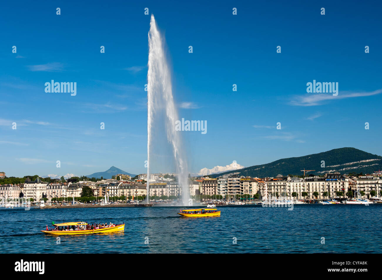 Yellow ferry boats on Lake Geneva with Jet d'Eau and Mont Blanc mountain range behind, Geneva ...