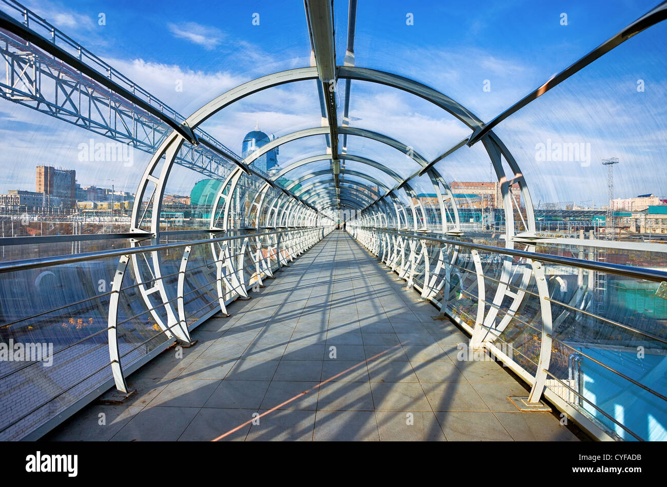 Steel and glass bridge for pedestrians crossing over the railway tracks ...