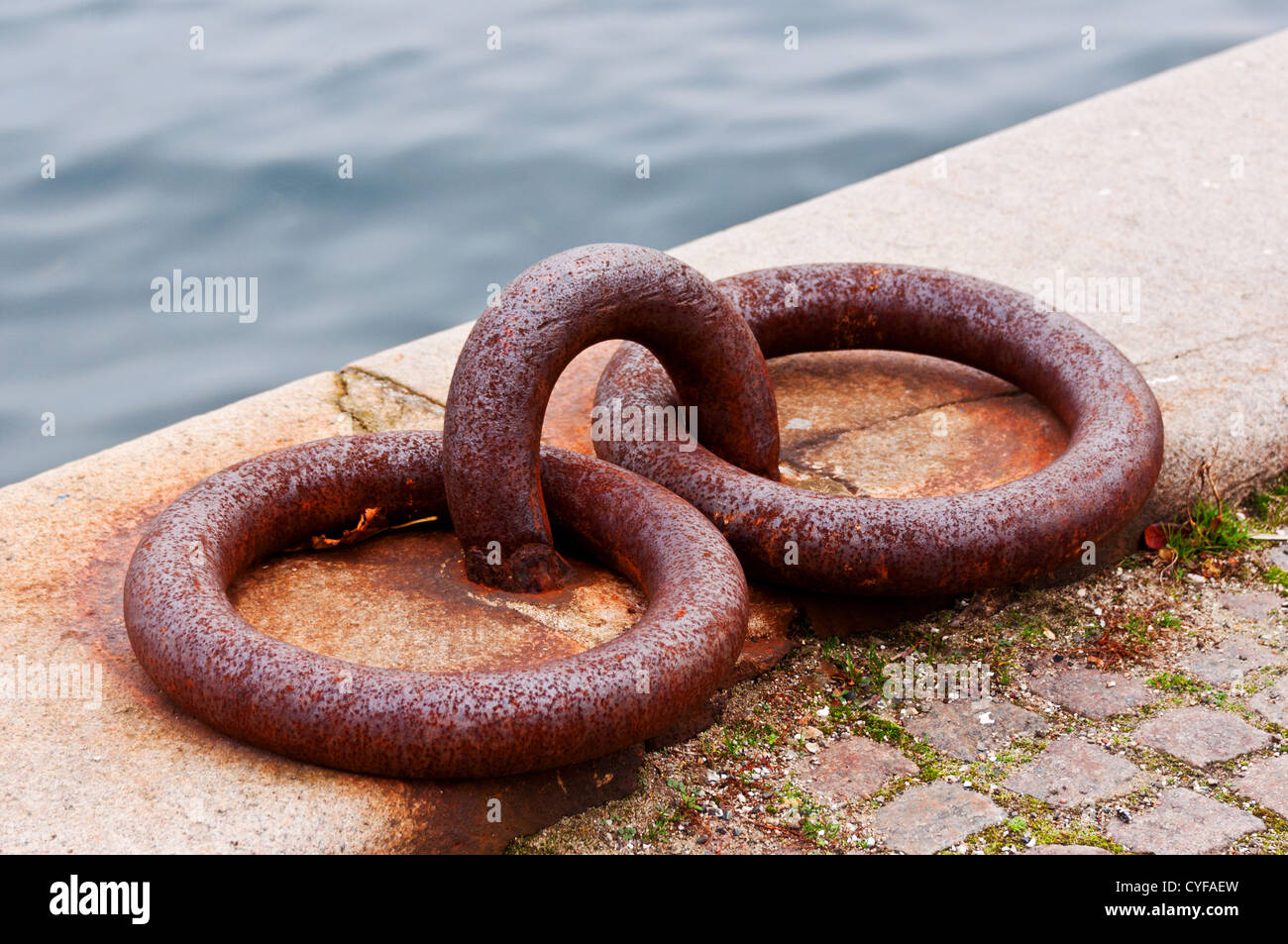 Heavily rusted iron mooring rings with the harbor Stock Photo - Alamy