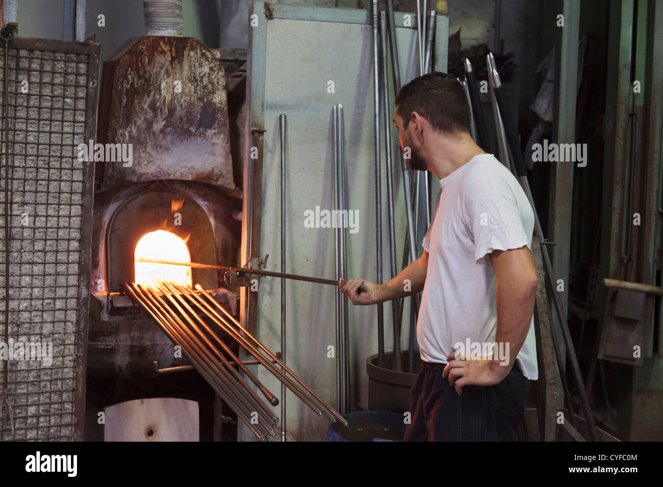 Worker in a glass factory in Murano in Venice heating glass in a ...