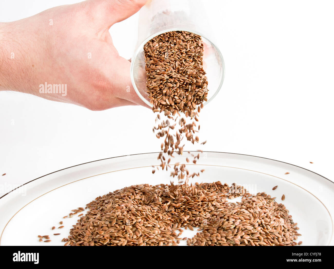 A hand holding a glass pouring out seeds on a plate Stock Photo - Alamy