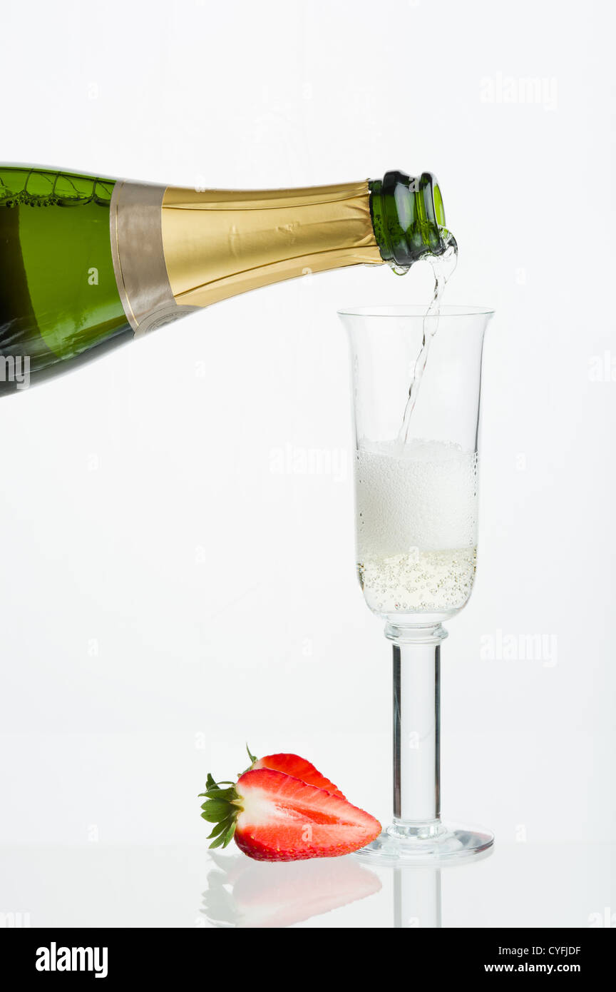 Pouring sparkling wine, split strawberry, reflection and white ...