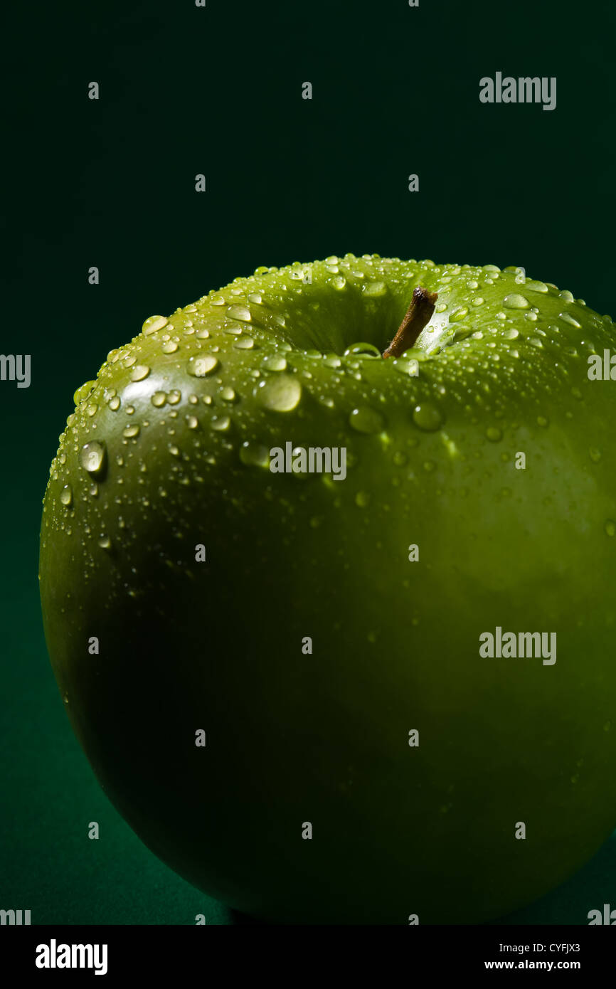 One green apple, water drops and green background Stock Photo - Alamy