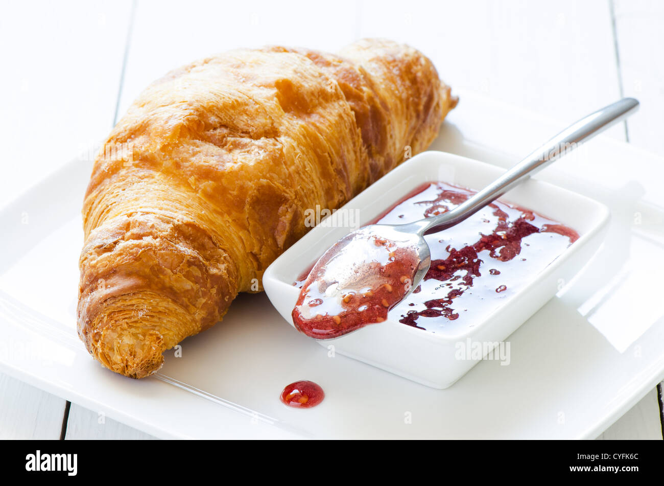 Croissant with raspberry jem on white wooden table Stock Photo - Alamy