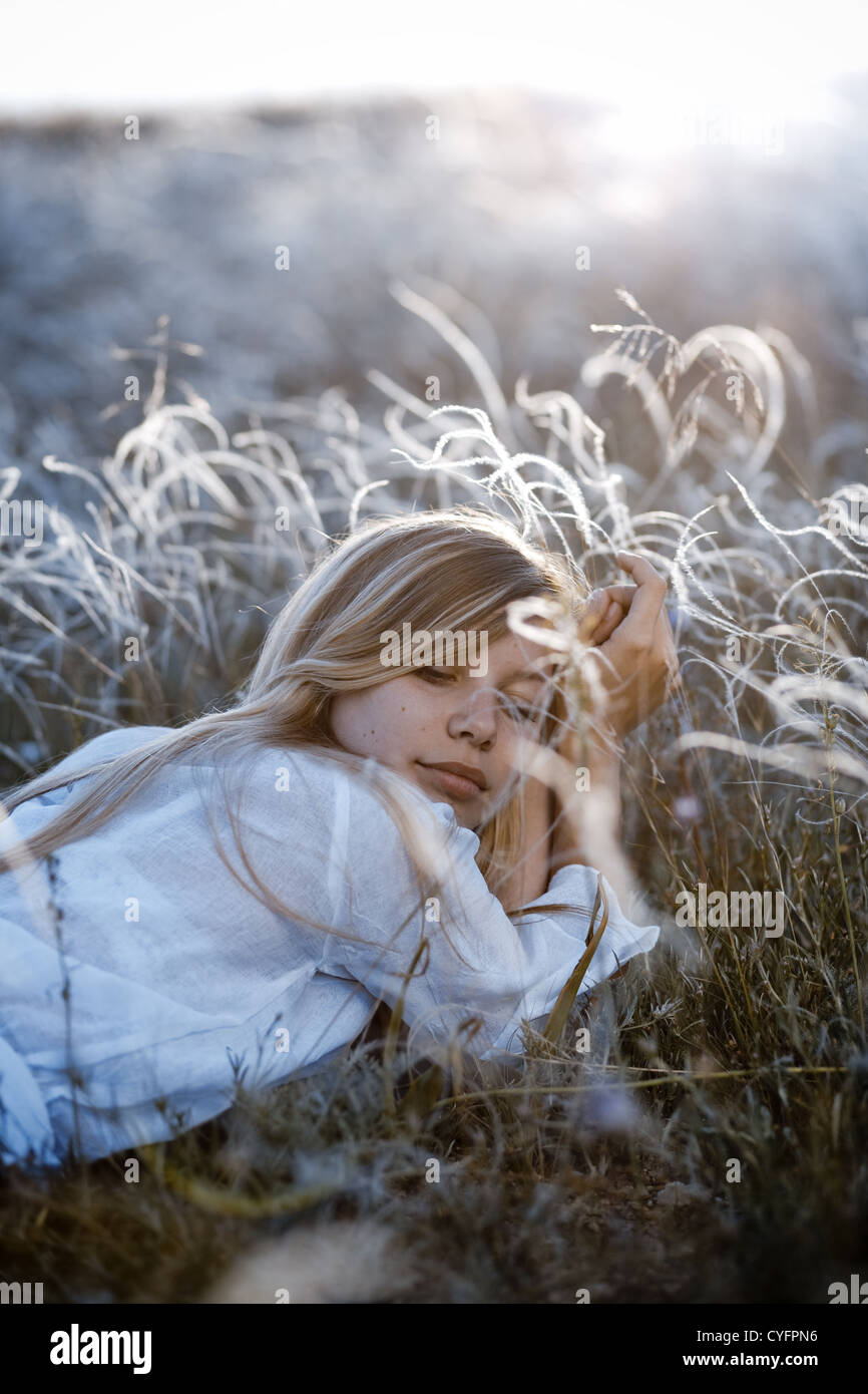 Girl lying in field of feather grass in soft evening sunshine Stock ...