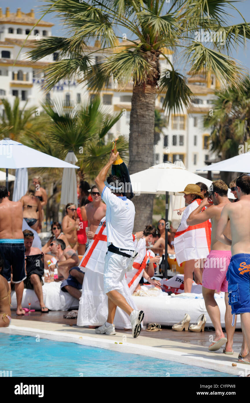 Waiter carrying large bottle of champagne on shoulder to clients at ...