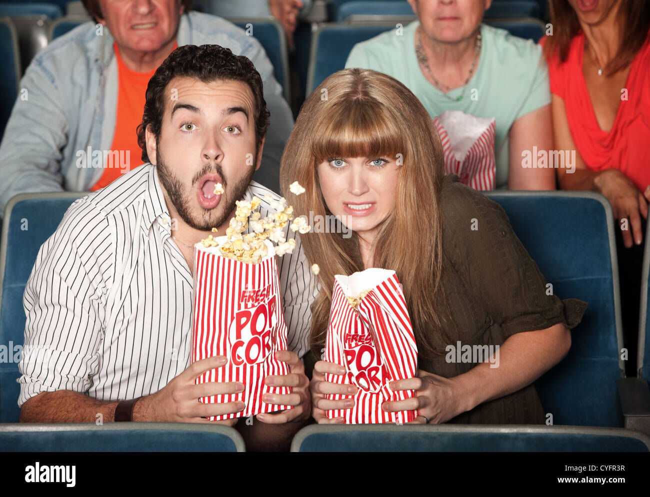 Scared Caucasian couple in theater spill their popcorn Stock Photo - Alamy
