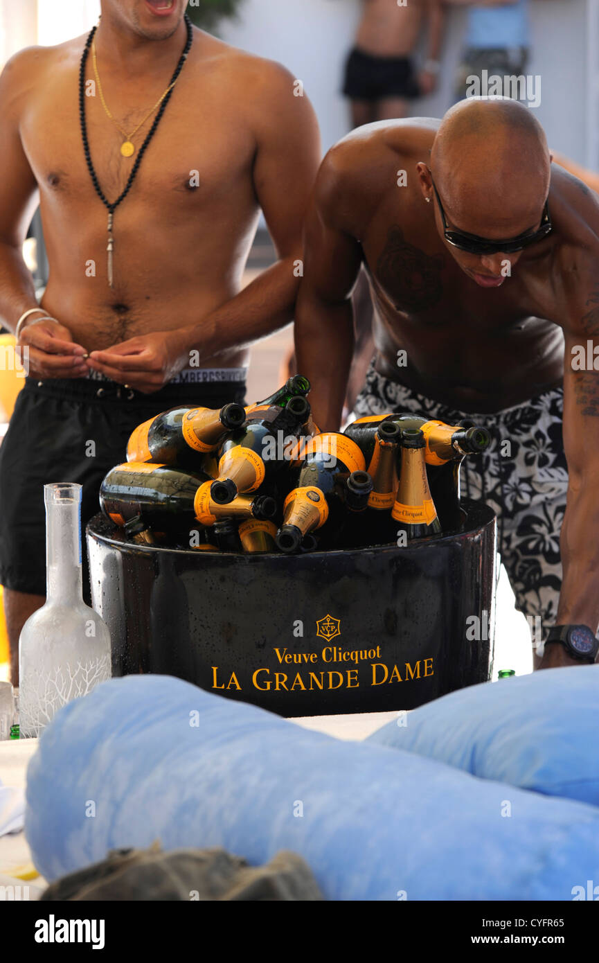 Party goers standing in front of dozens of empty bottles of champagne ...