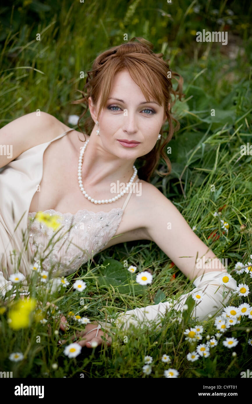Bride relaxing in fresh grass with flowers Stock Photo - Alamy