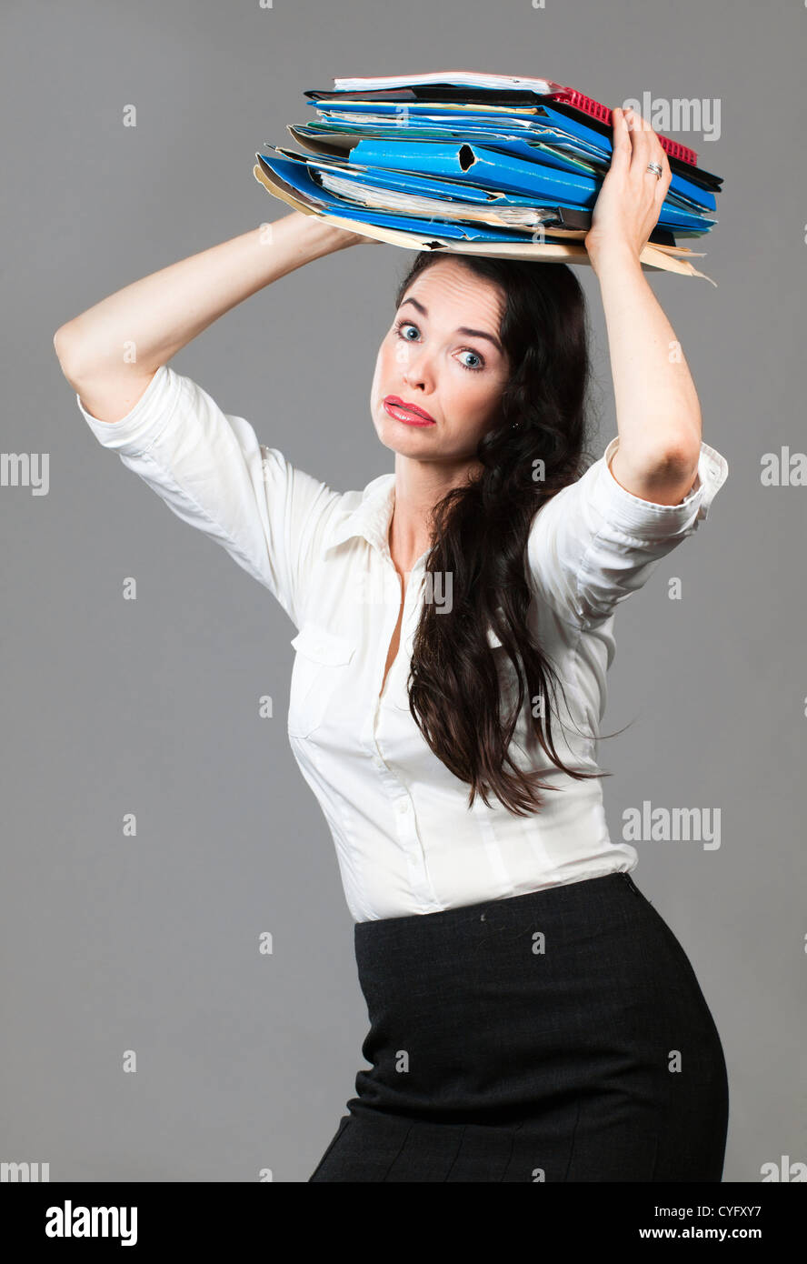 Portrait of a tired and overworked business woman carrying paperwork on ...