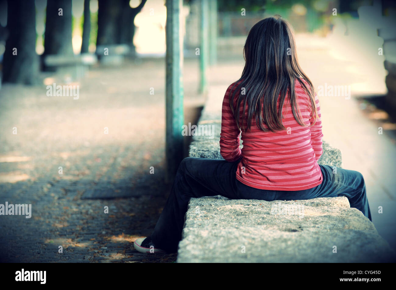 Girl sitting on stone bench Stock Photo - Alamy