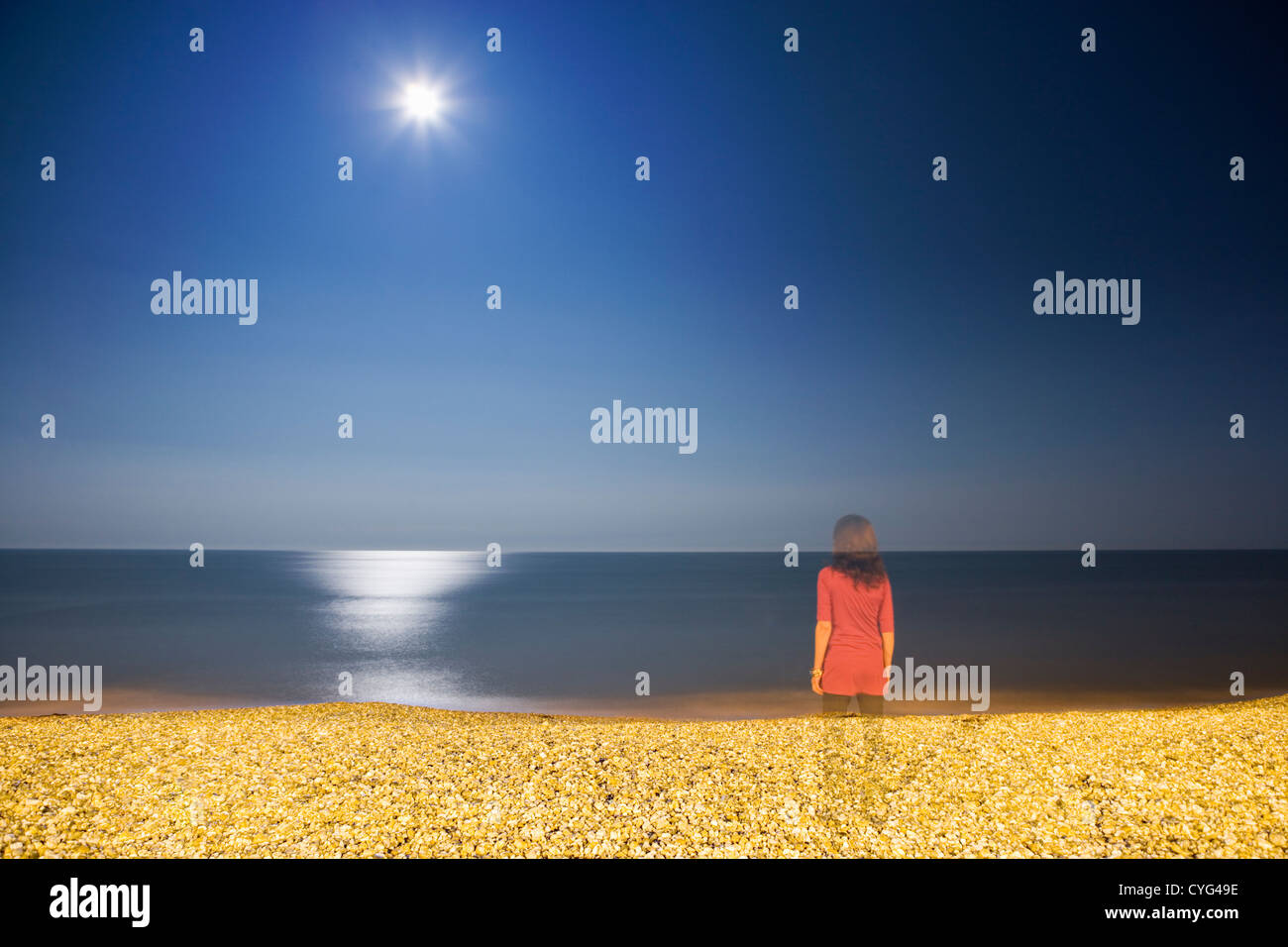 Woman standing on moonlit beach at night Stock Photo - Alamy