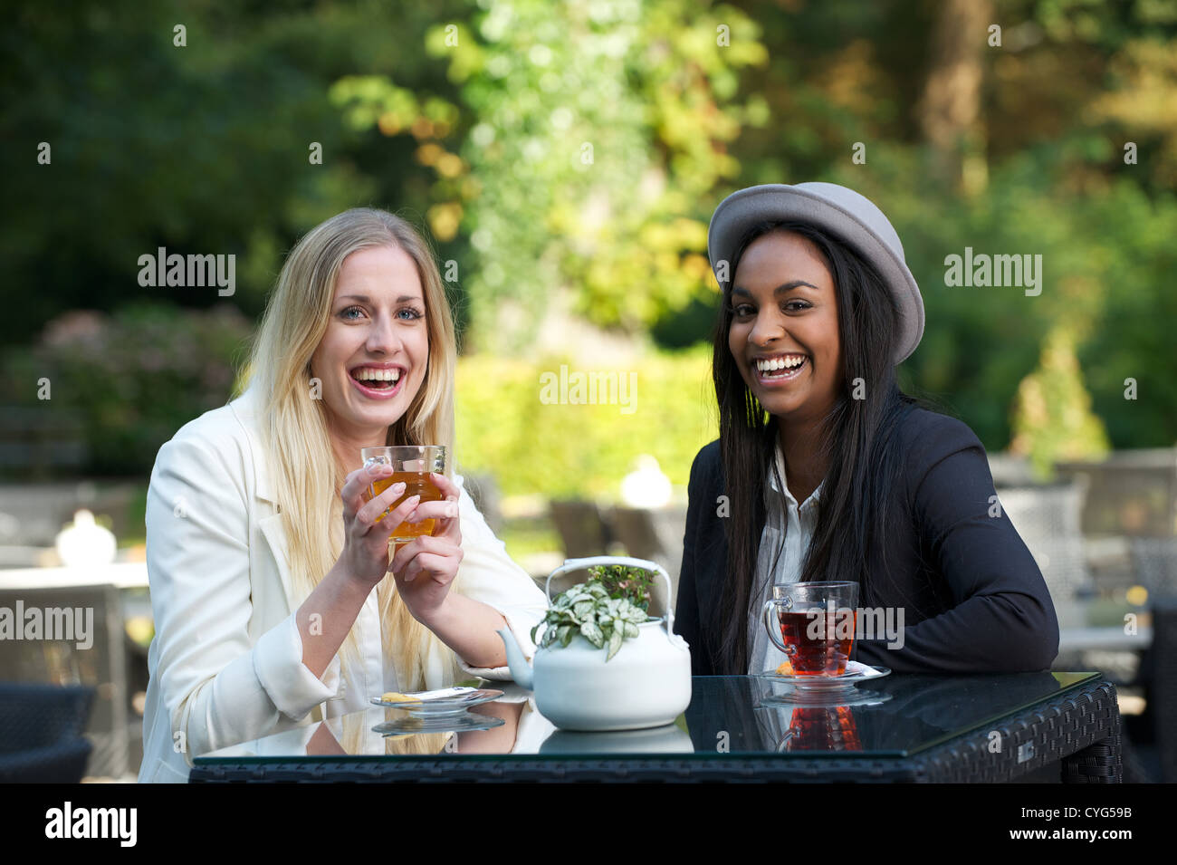Two women friends laughing and having a good time while drinking tea ...