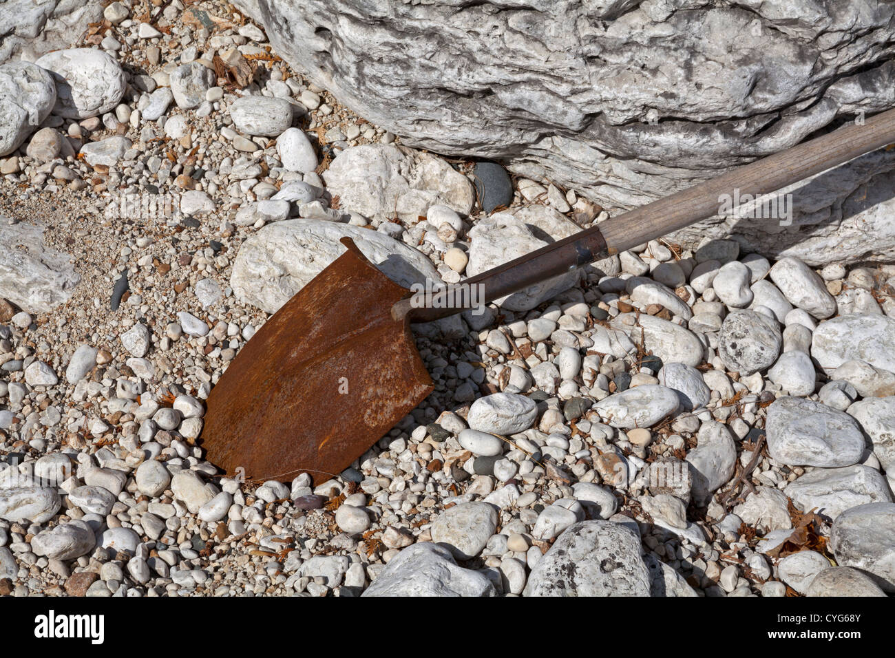 A rusty shovel sits on a rocky shoreline Stock Photo - Alamy