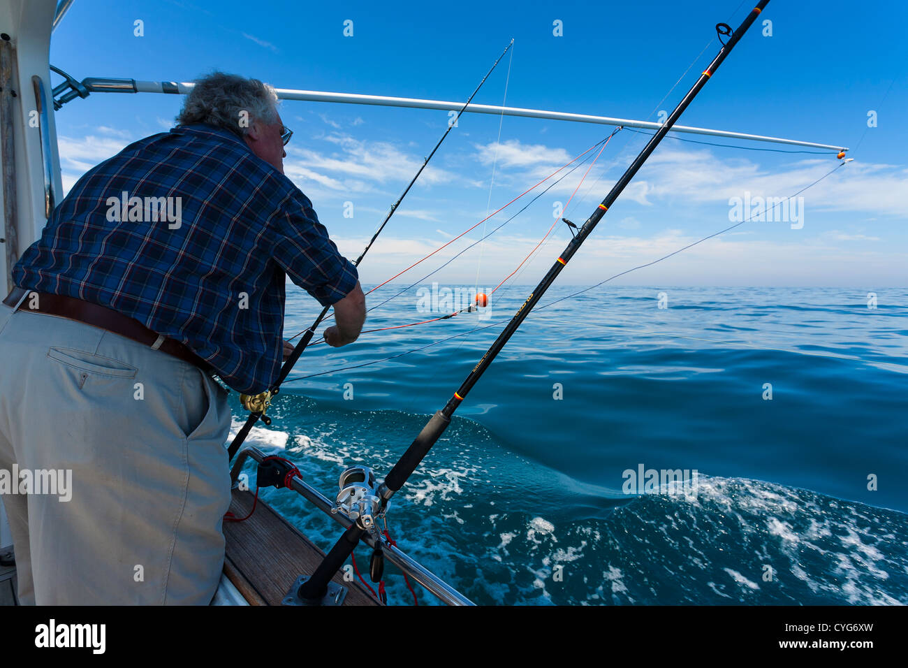 Angler sets lines for "trolling" a lure behind a moving boat to catch ...