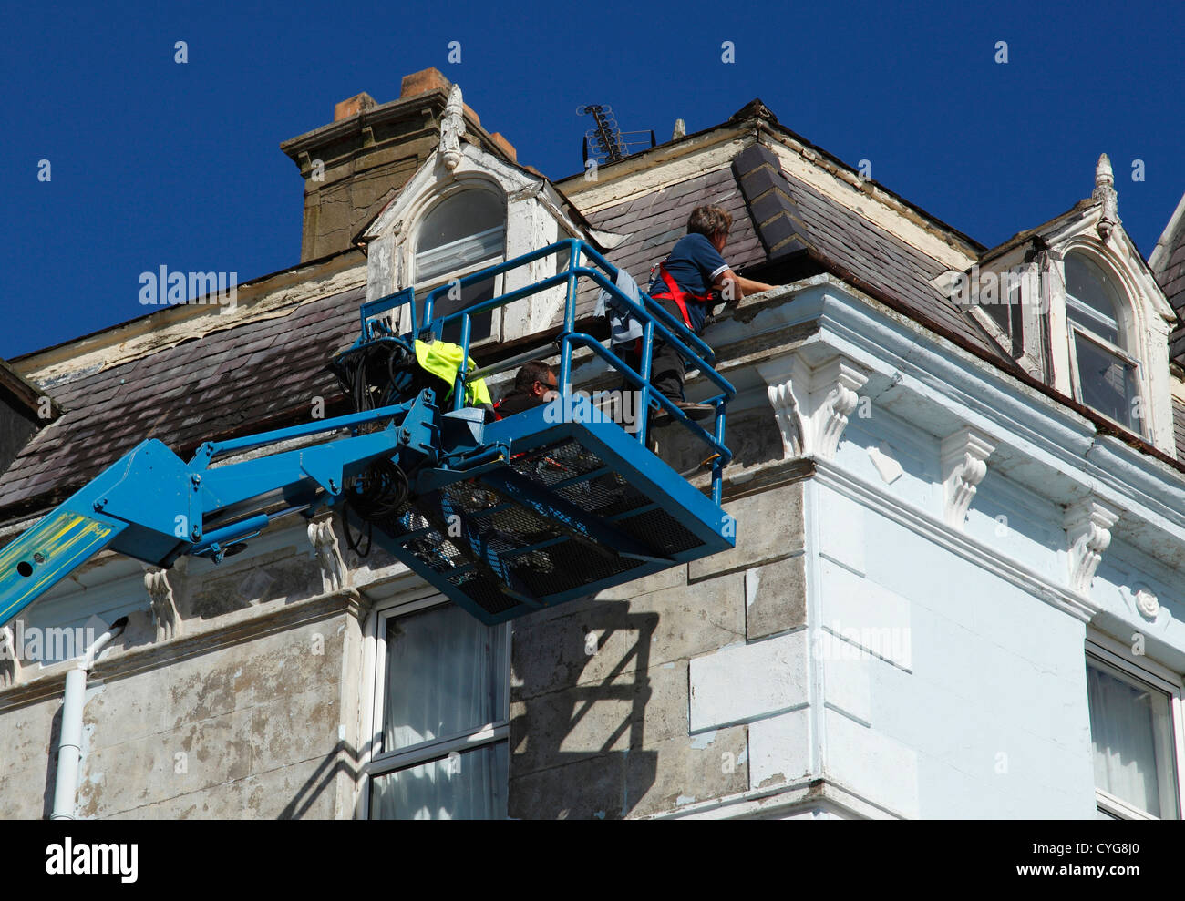 Workmen using a cherry picker to repair gutters on property in the U.K ...