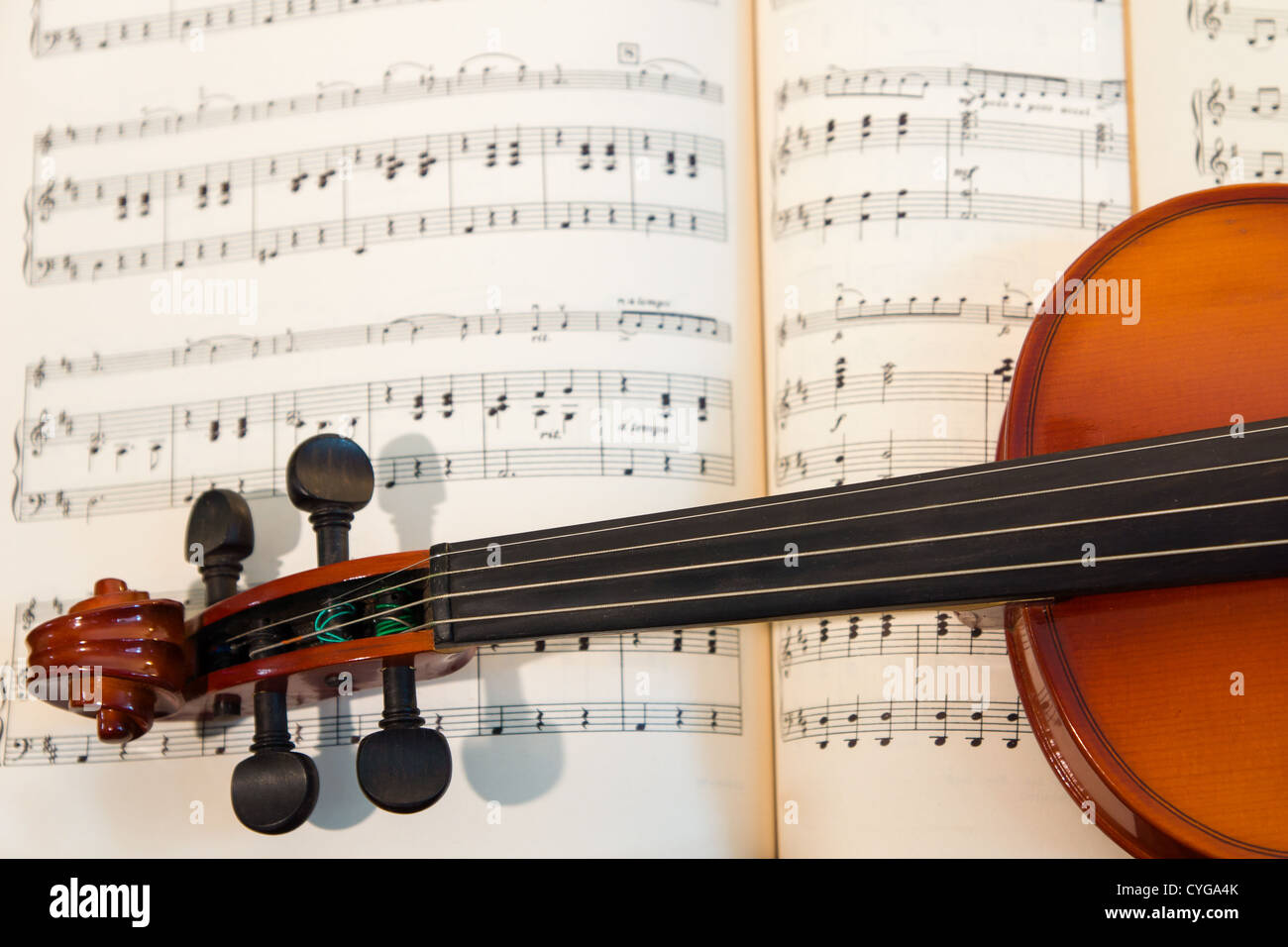 A detail of the neck and scroll of a violin resting against some ...