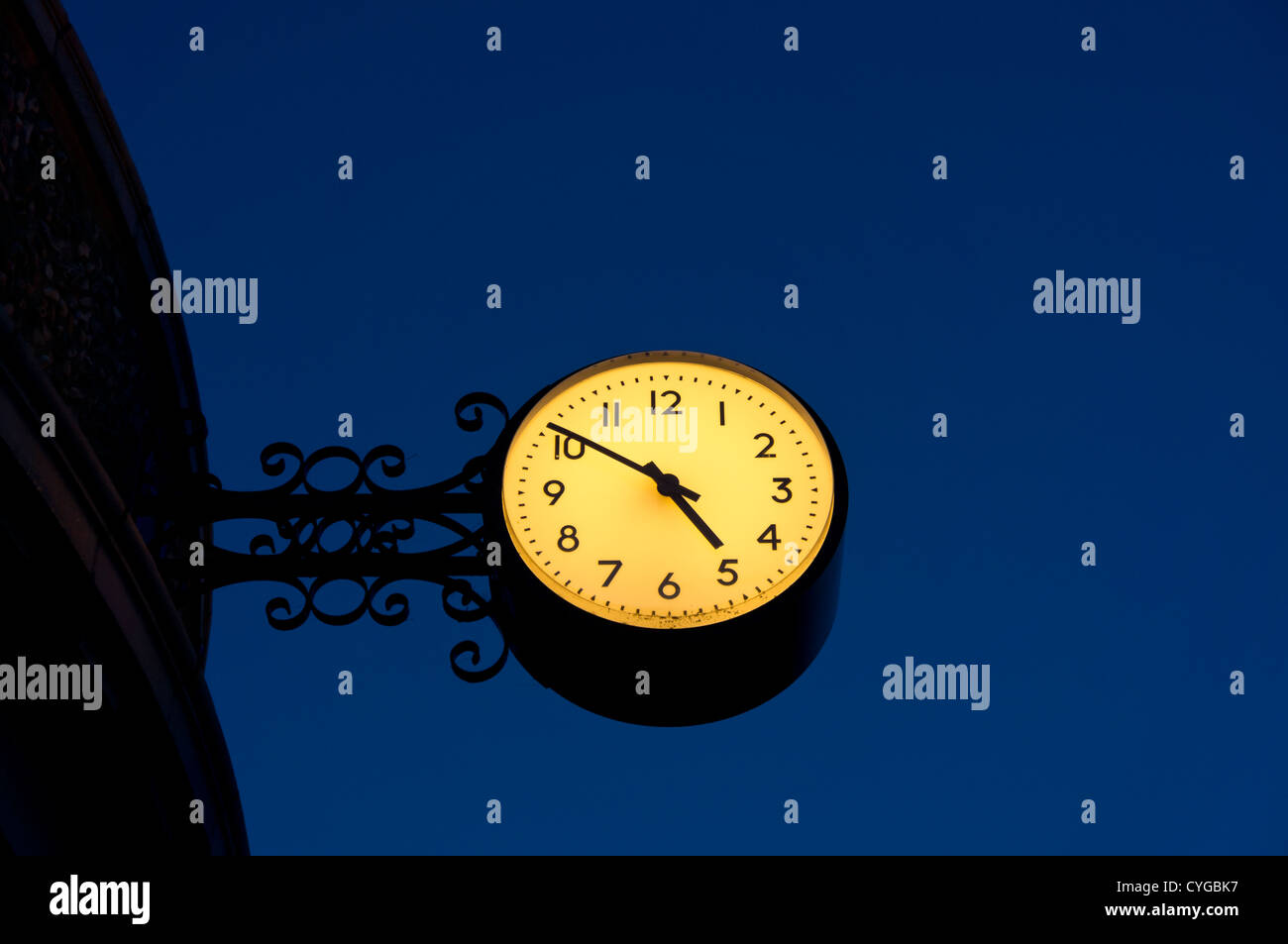 An ornate clock with an illuminated face on the side of a building in ...