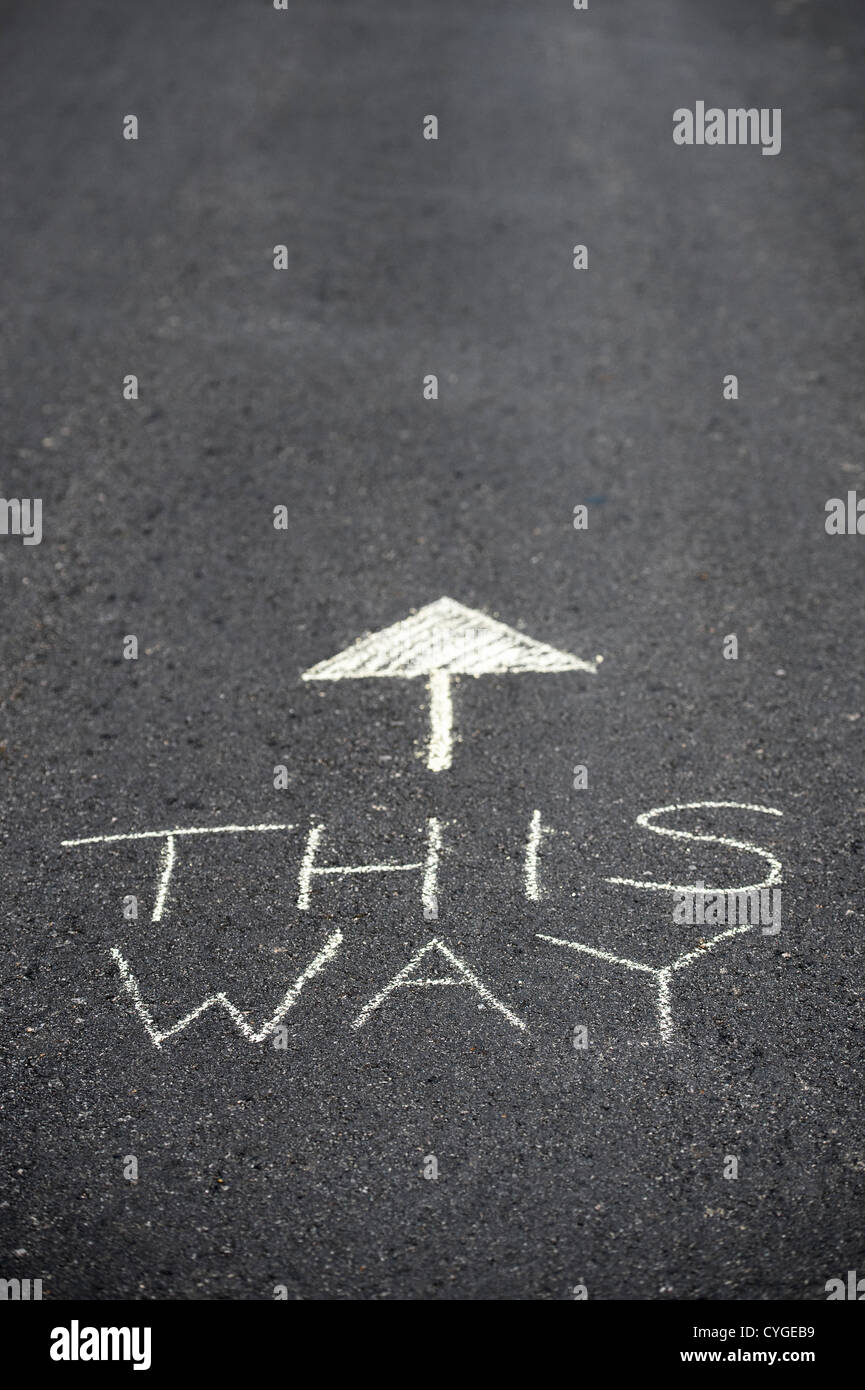 THIS WAY and Arrow chalked on a road Stock Photo - Alamy