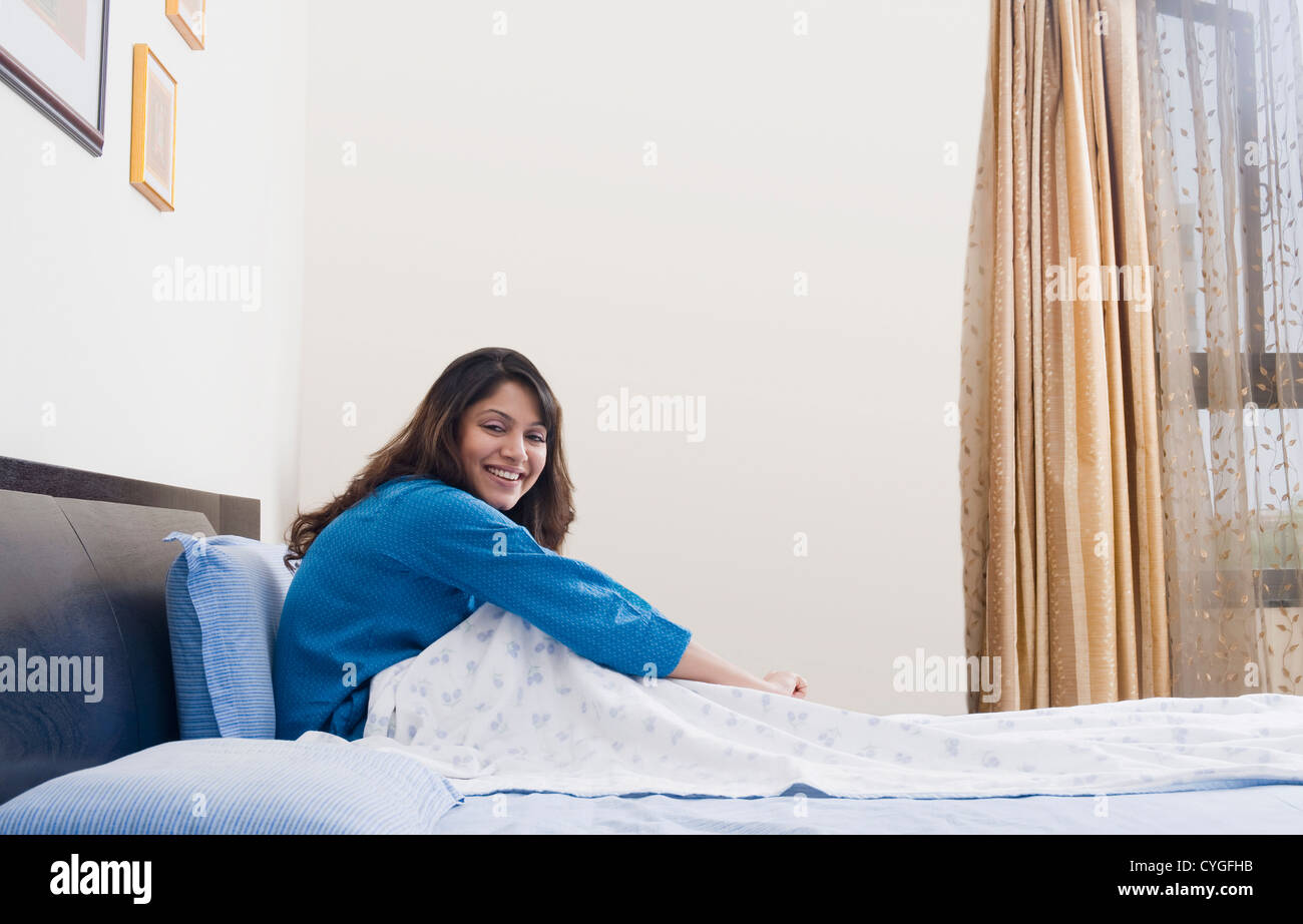 Woman sitting on the bed and smiling Stock Photo - Alamy