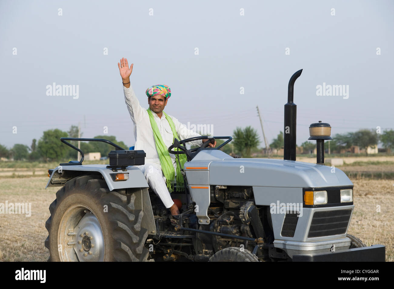 Farmer ploughing a field with a tractor and waving his hand Stock Photo ...