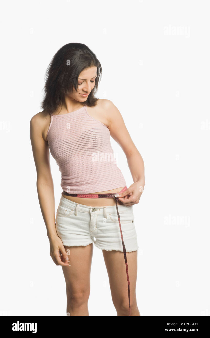 Woman measuring her waist with a tape measure Stock Photo - Alamy