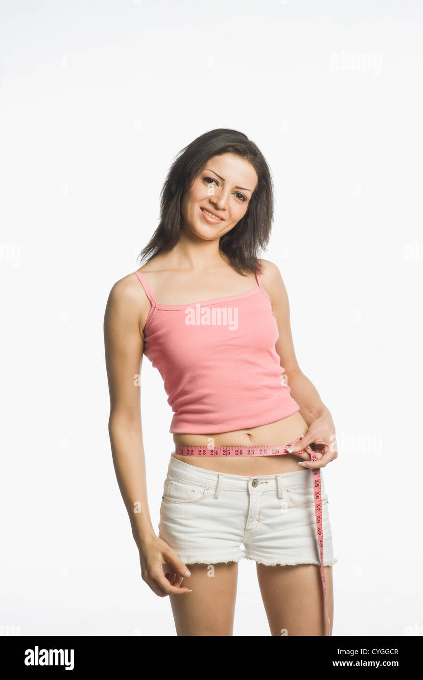Woman measuring her waist with a tape measure Stock Photo - Alamy