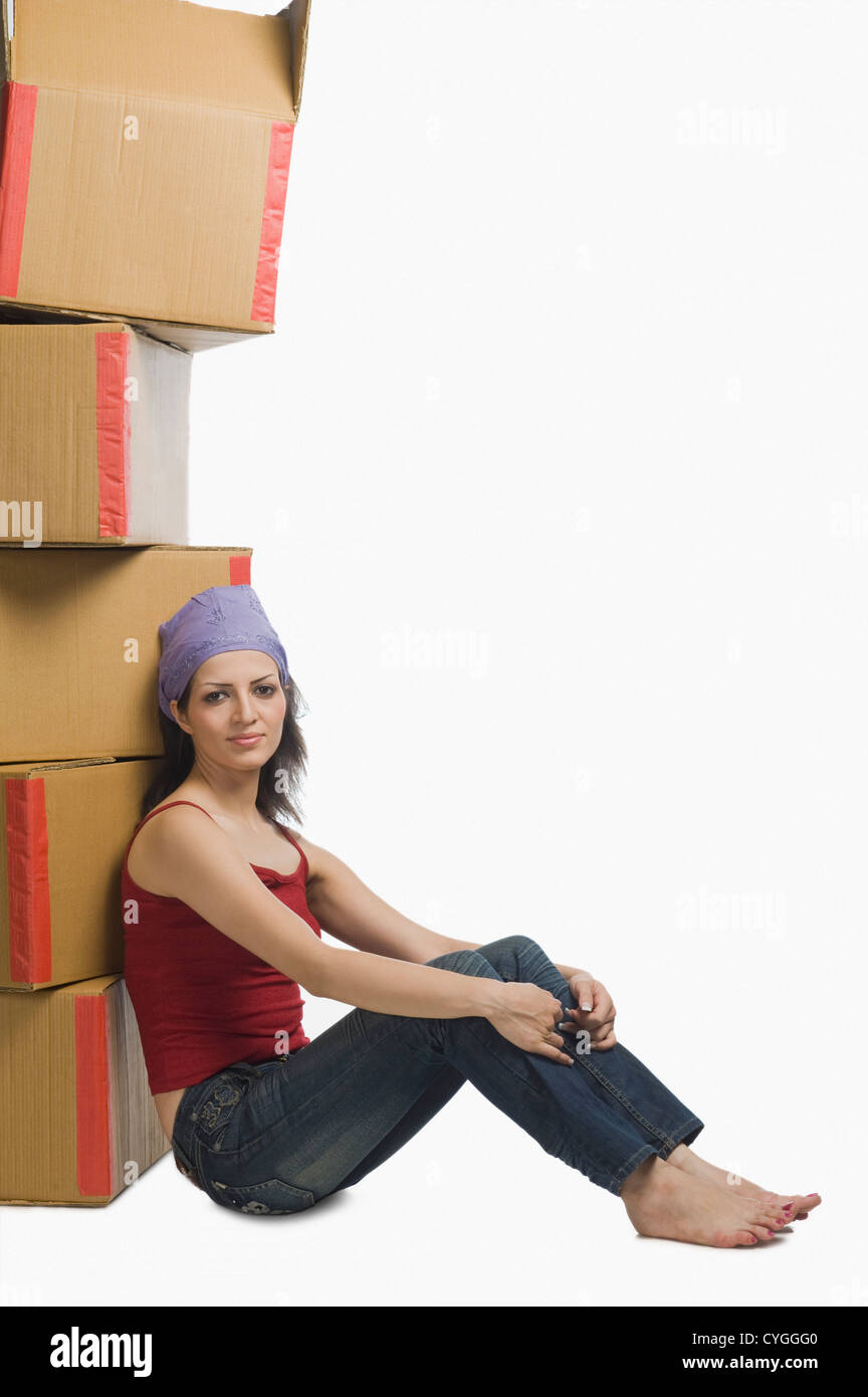 Portrait of a woman leaning against cardboard boxes Stock Photo - Alamy