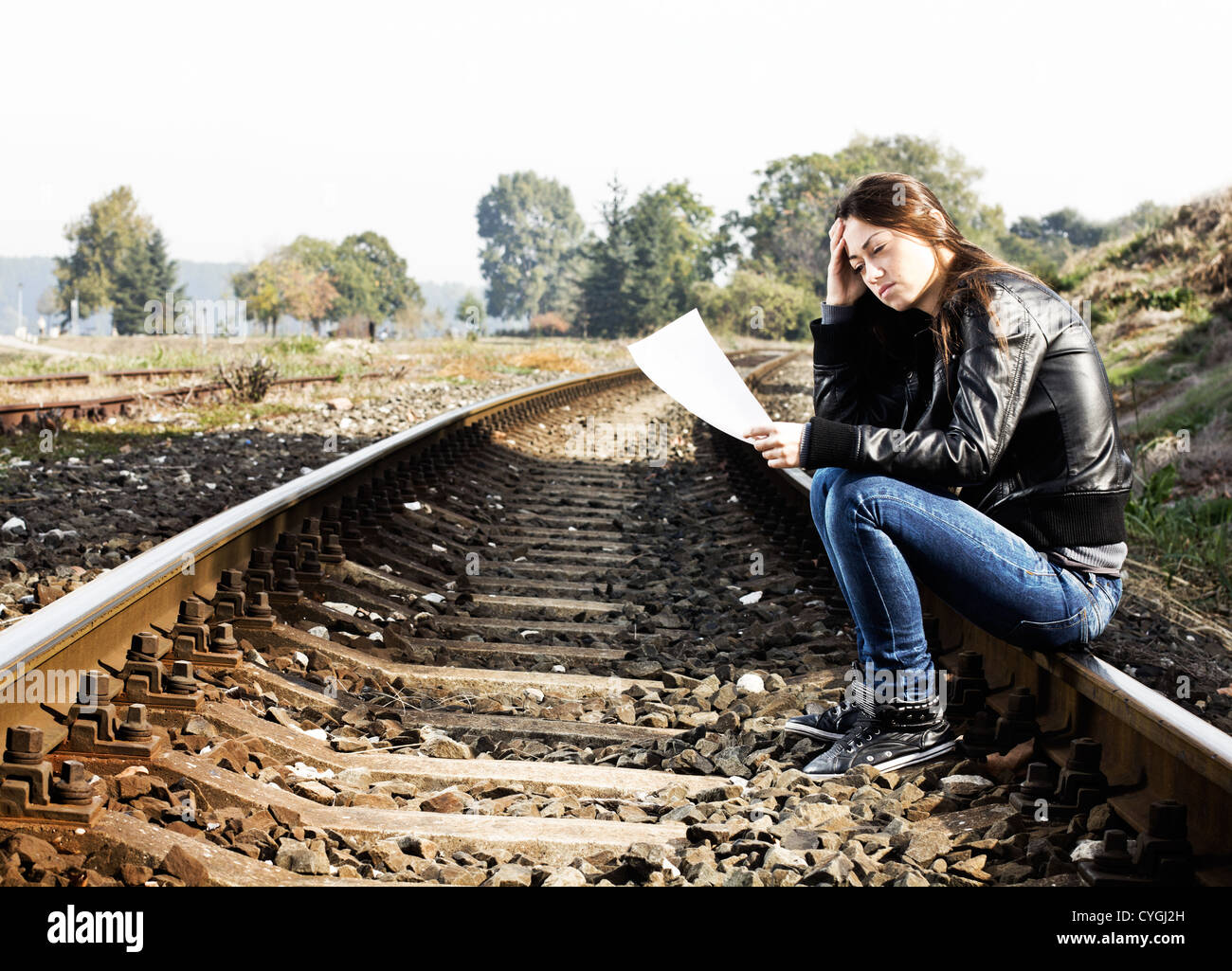 Depressed and lonely teenage girl reading the letter on railroads Stock ...
