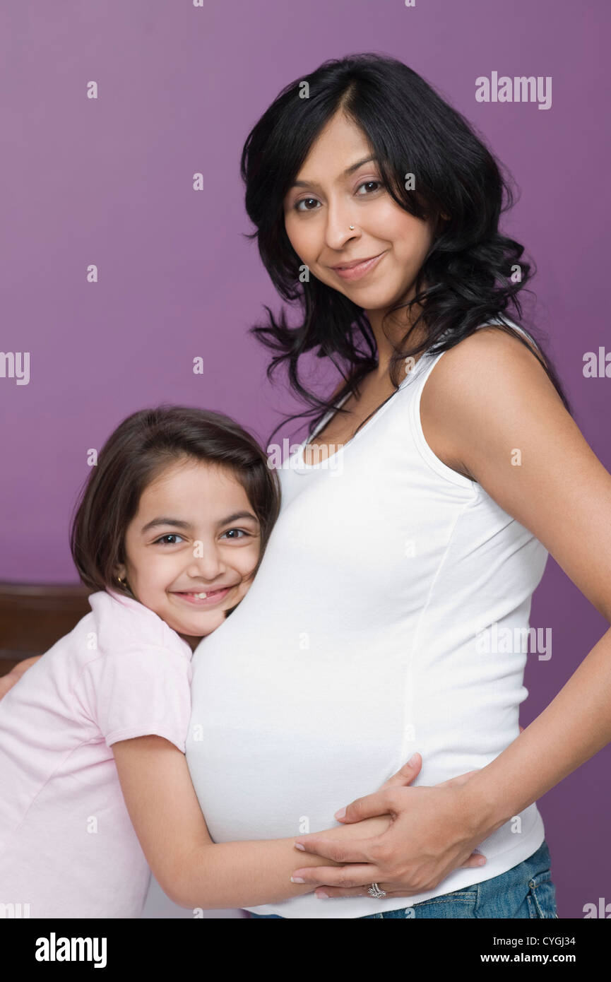 Girl hugging her pregnant mother and smiling Stock Photo - Alamy