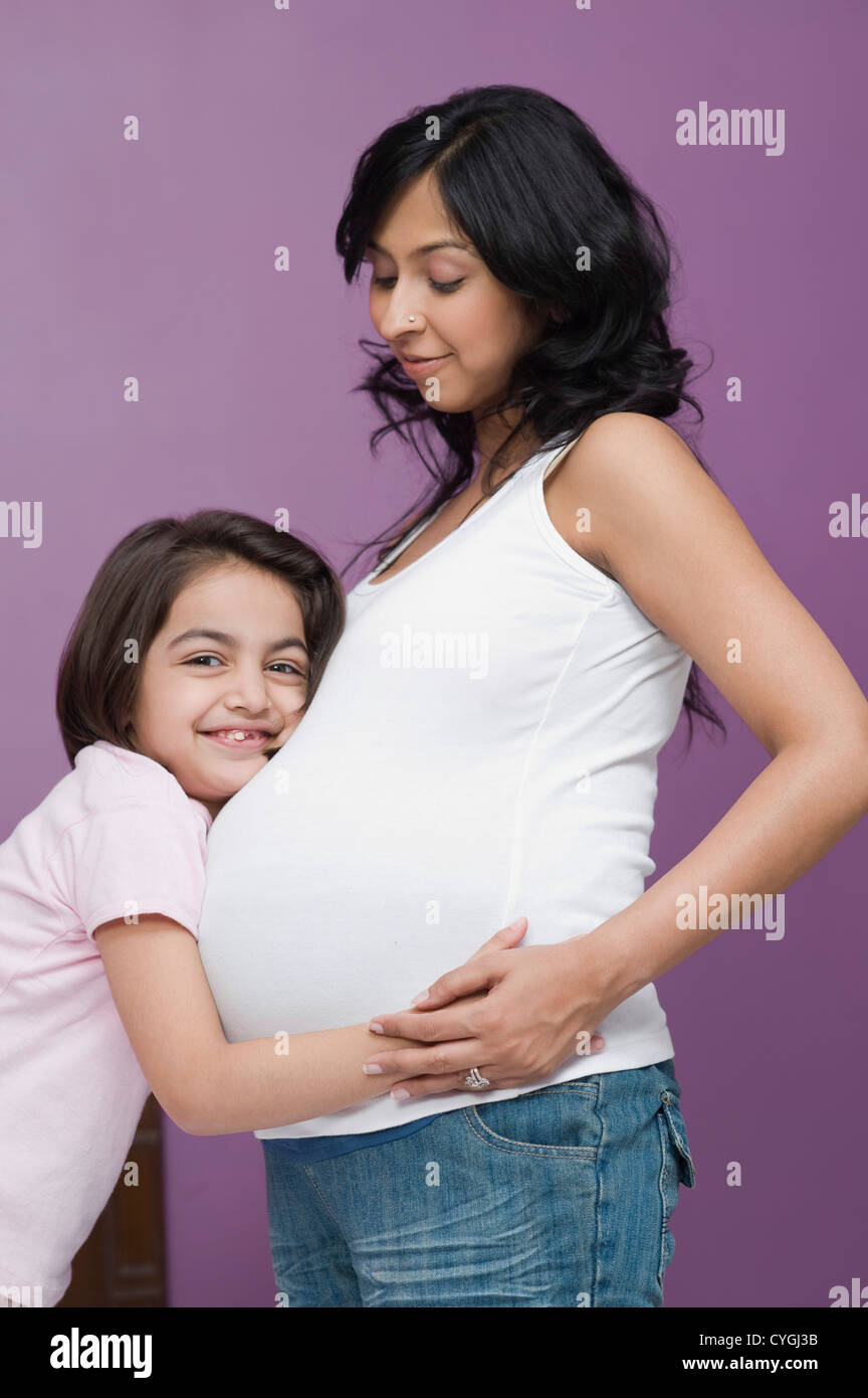 Girl hugging her pregnant mother and smiling Stock Photo - Alamy